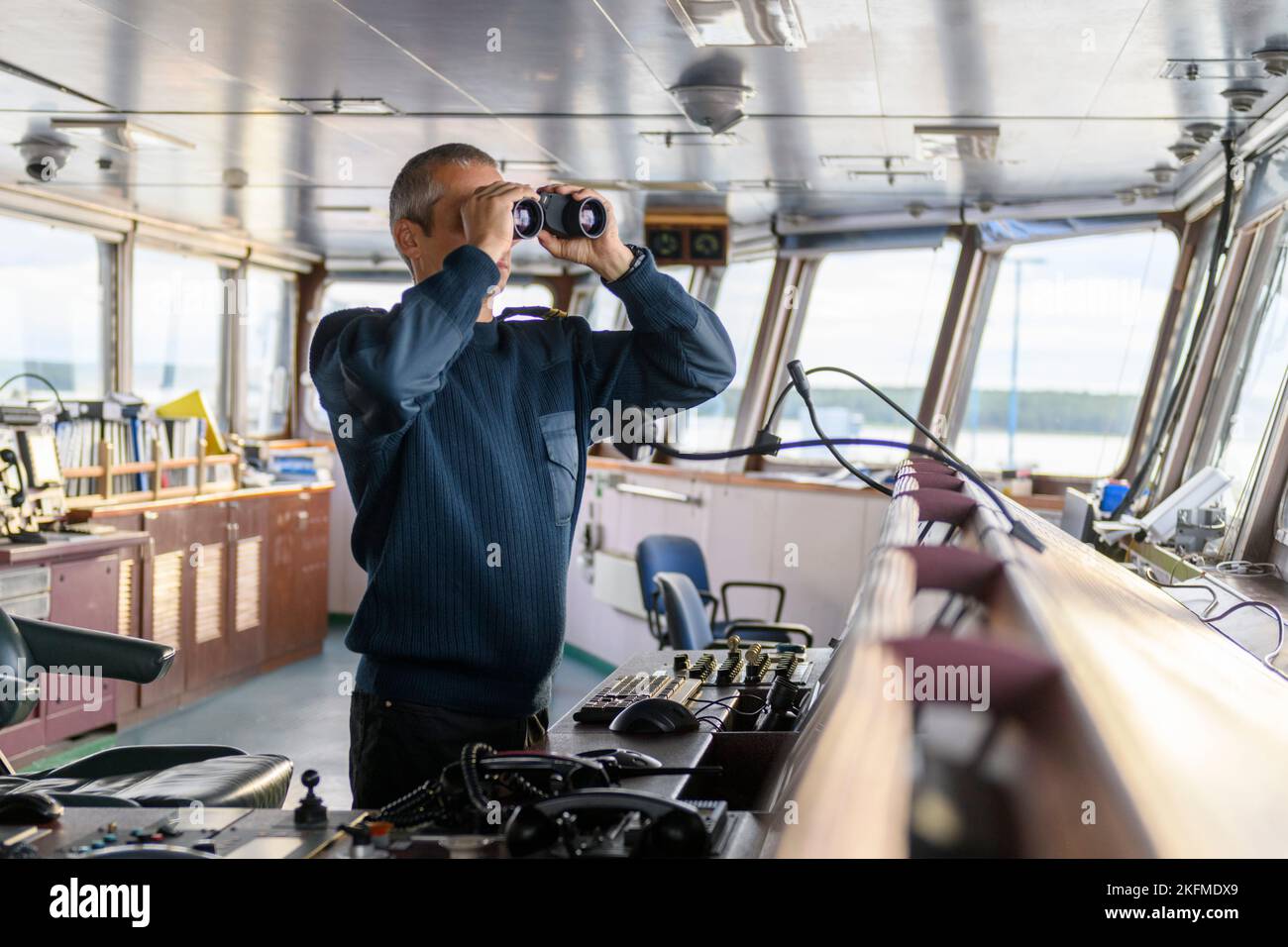 Deck officer with binoculars on navigational bridge. Seaman on board of ...