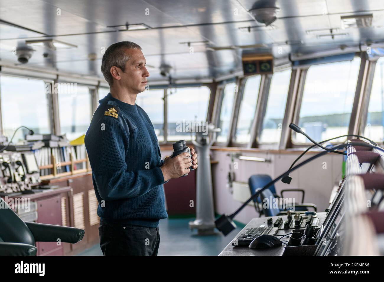 Deck officer with binoculars on navigational bridge. Seaman on board of ...