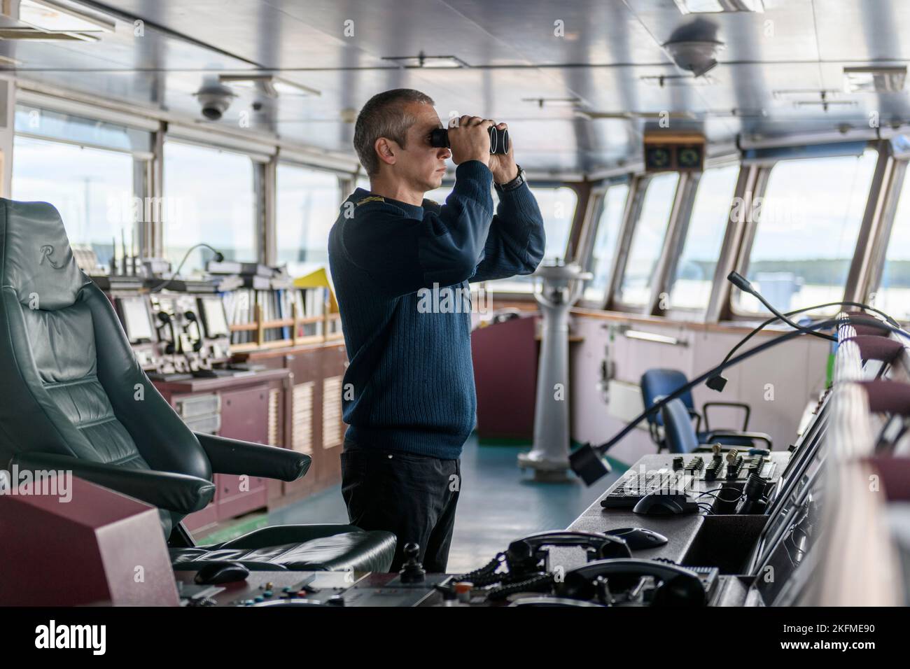 Deck officer with binoculars on navigational bridge. Seaman on board of ...
