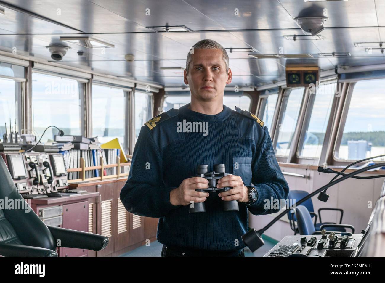 Deck officer with binoculars on navigational bridge. Seaman on board of ...