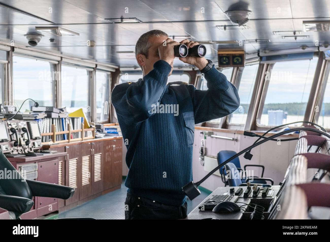 Deck officer with binoculars on navigational bridge. Seaman on board of ...