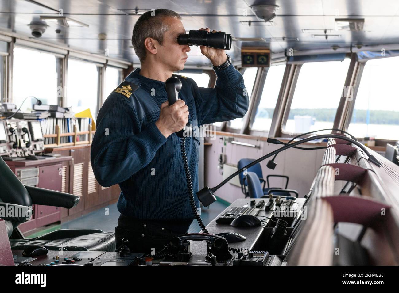 Deck officer with binoculars on navigational bridge. Seaman on board of ...