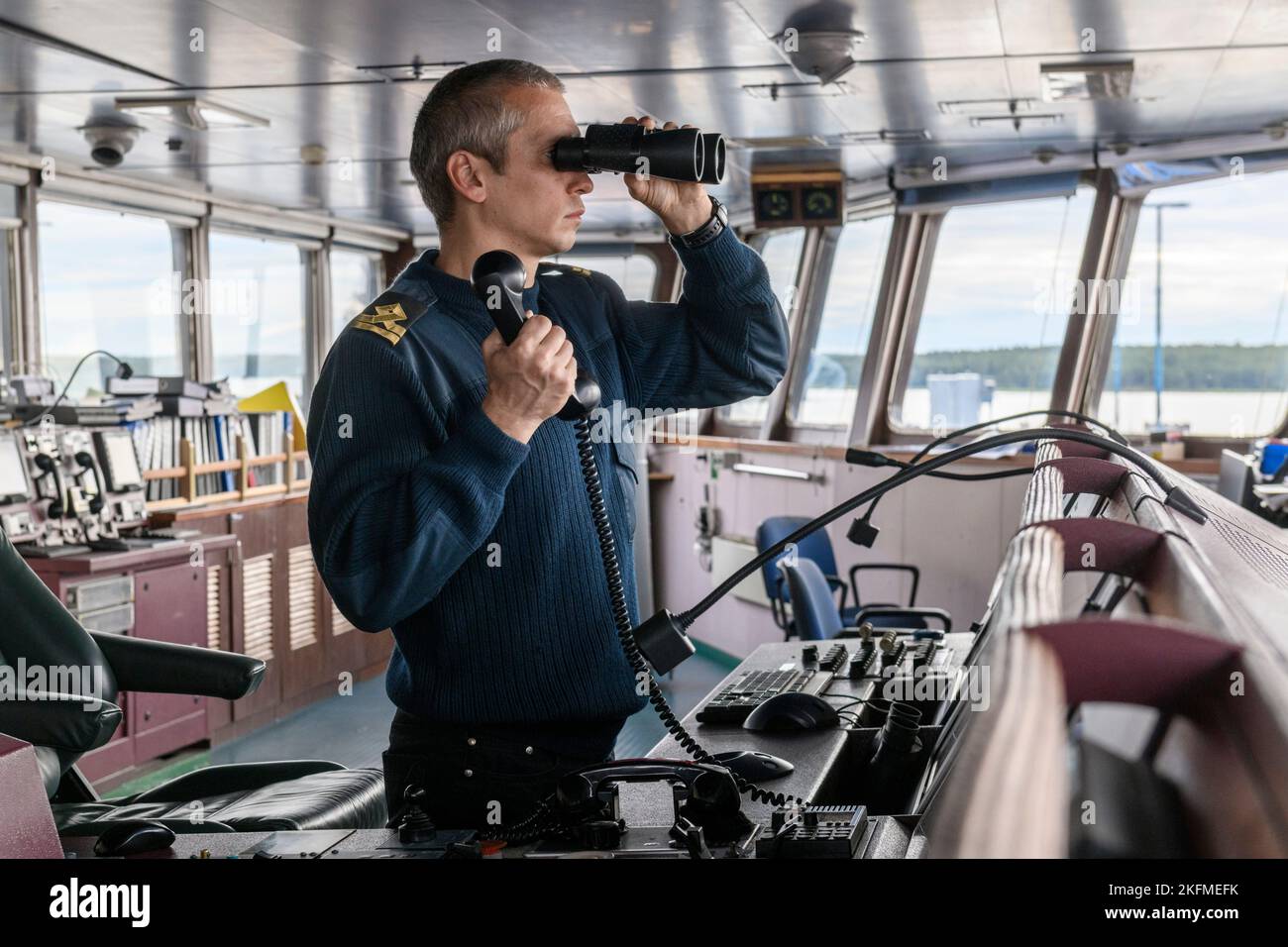 Deck officer with binoculars on navigational bridge. Seaman on board of ...