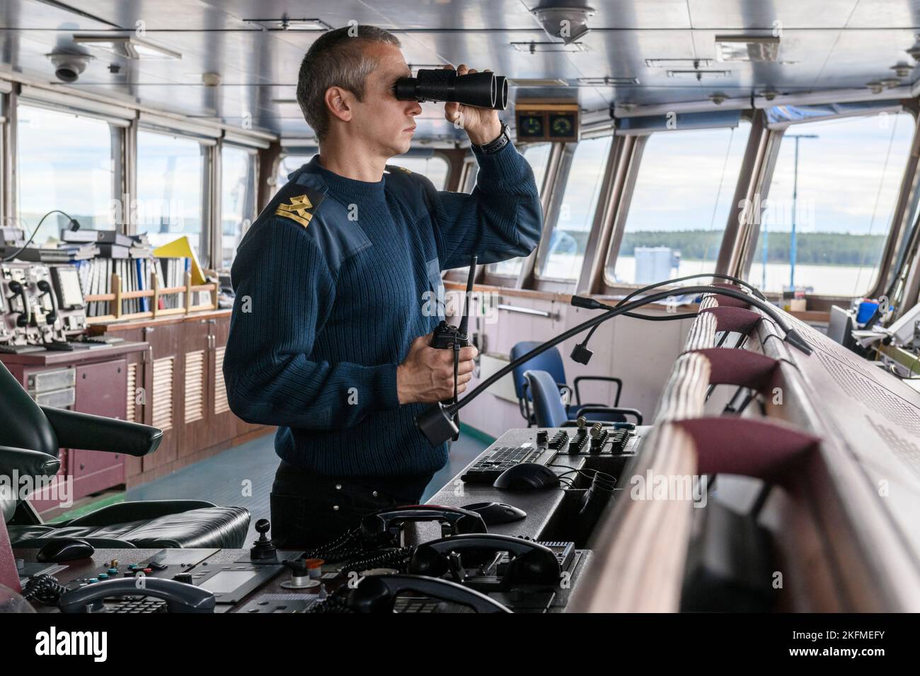 Deck officer with binoculars on navigational bridge. Seaman on board of ...