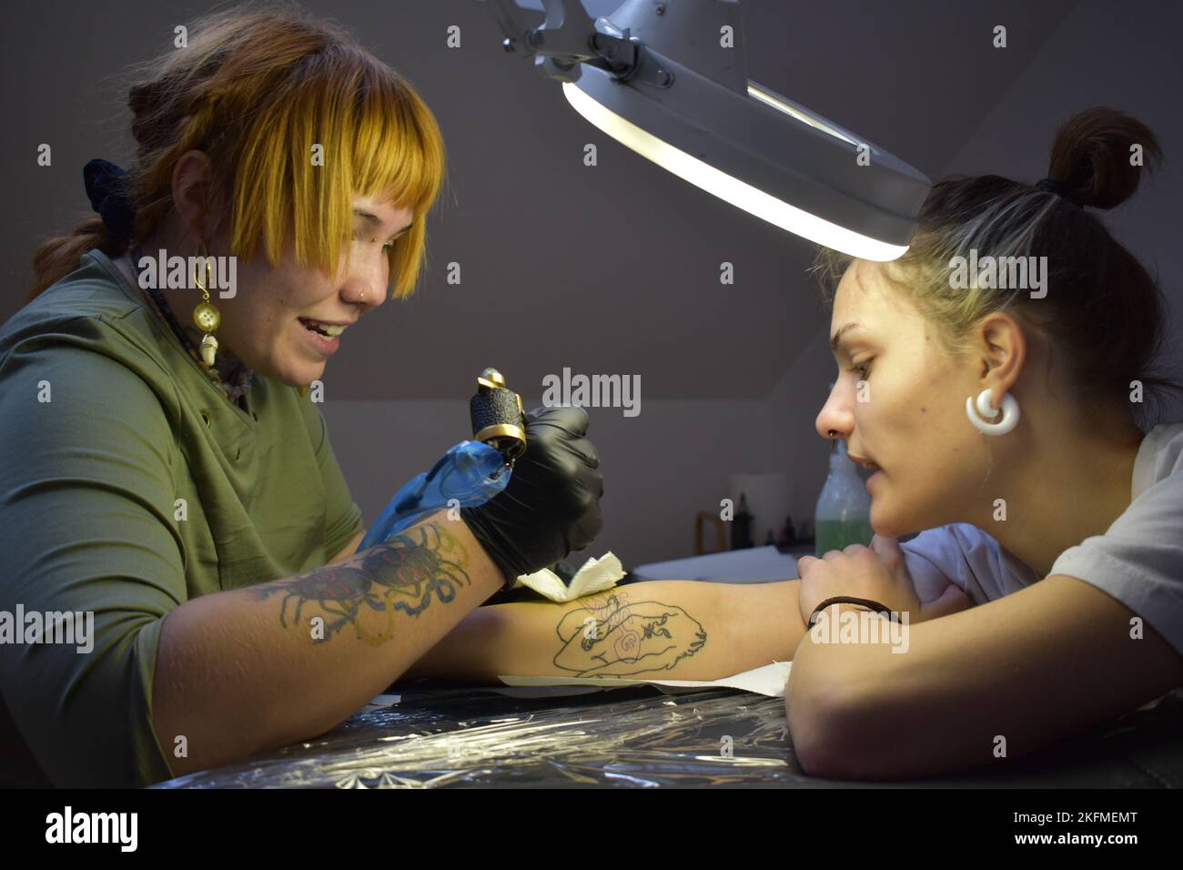 Girl getting tattoo from a tattoo artist Stock Photo - Alamy