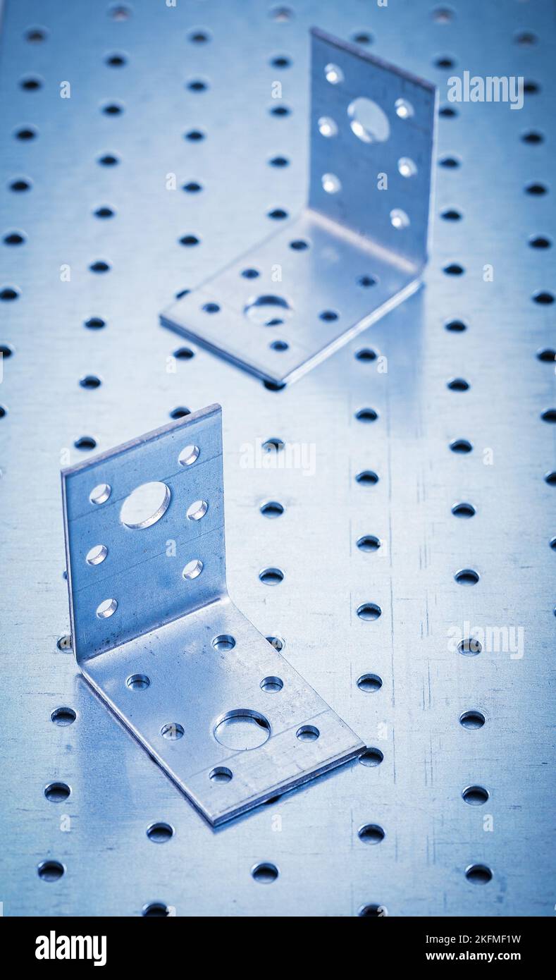 Stainless perforated angle fasteners on metallic background ...