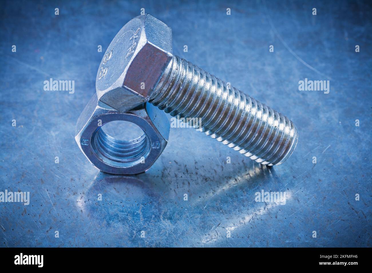 Threaded screwbolt and construction nut on metallic background top view ...