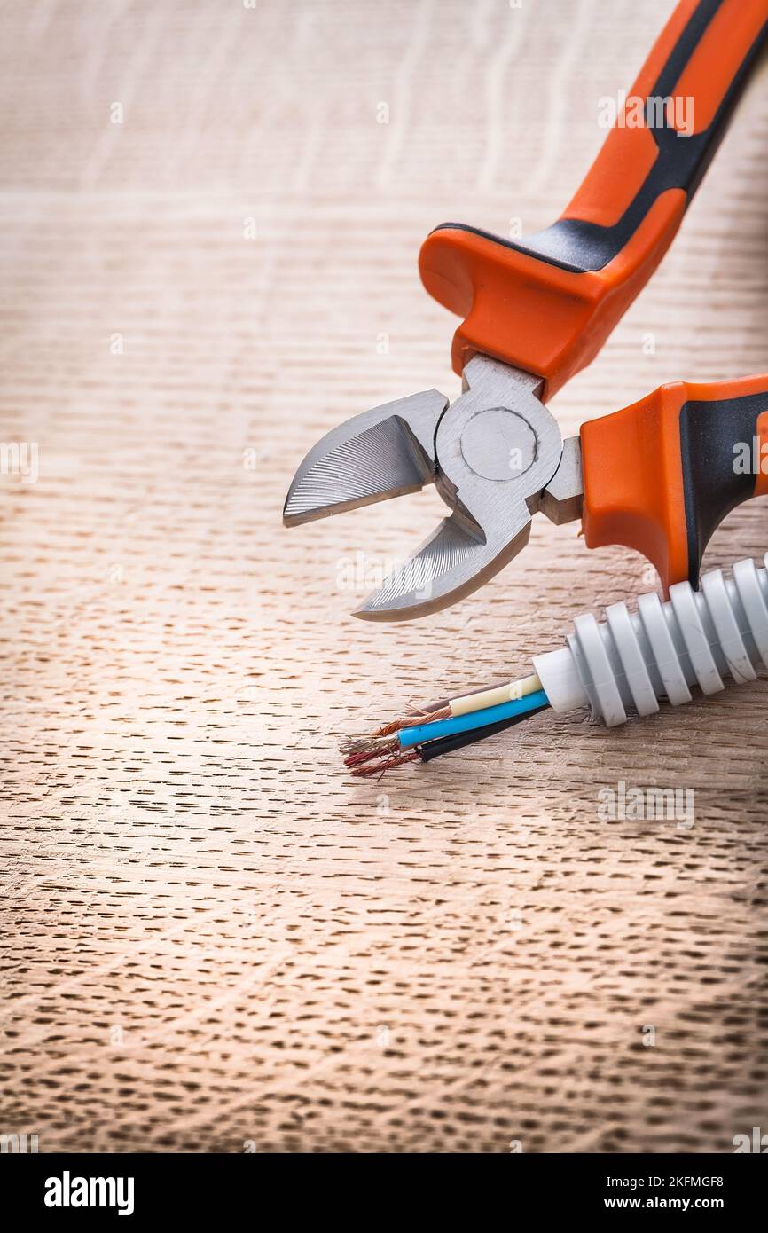 vertical view opened nippers and electrical cable on wooden board ...