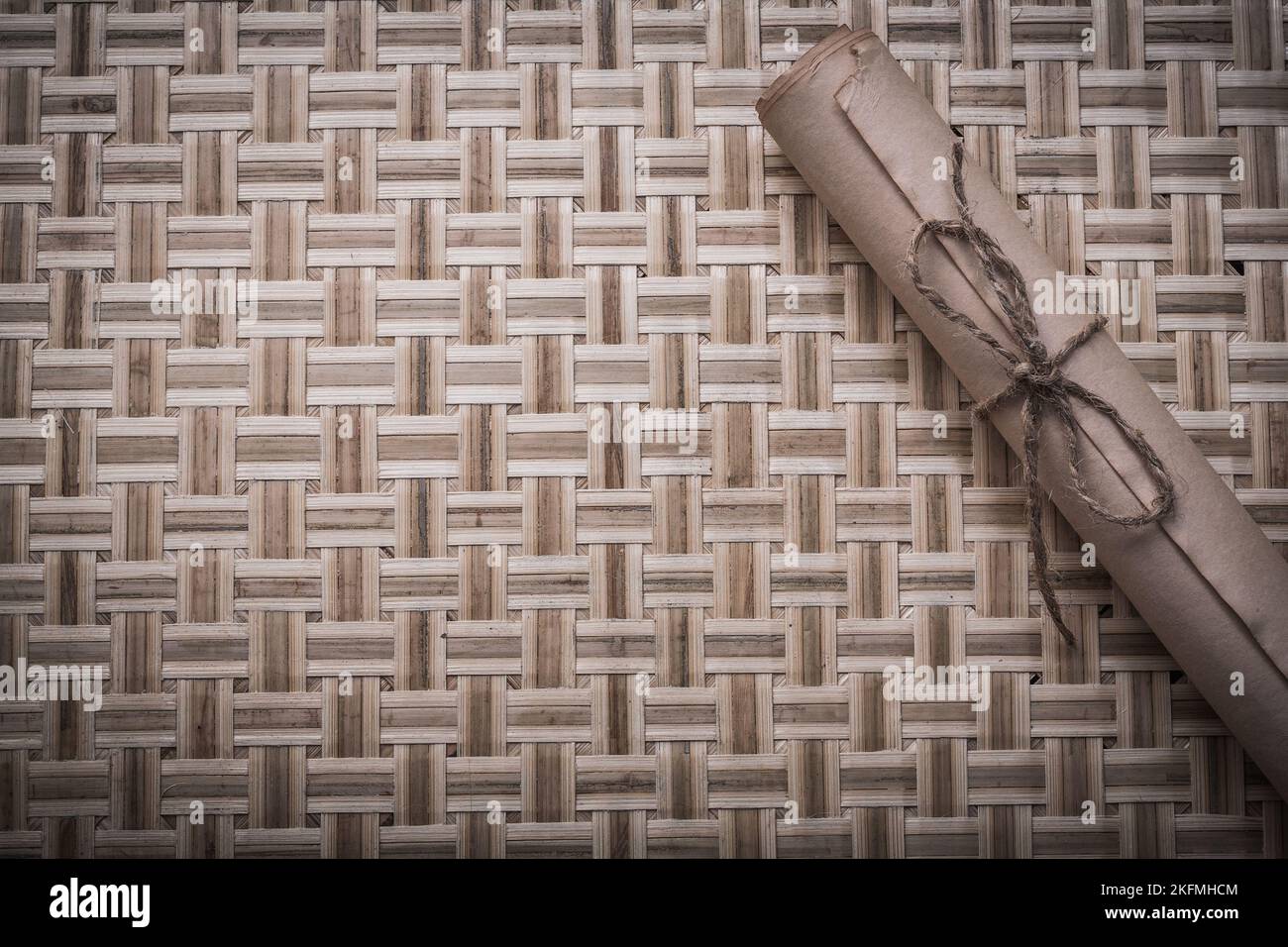 Vintage rolled corded paper on woven wooden matting Stock Photo - Alamy