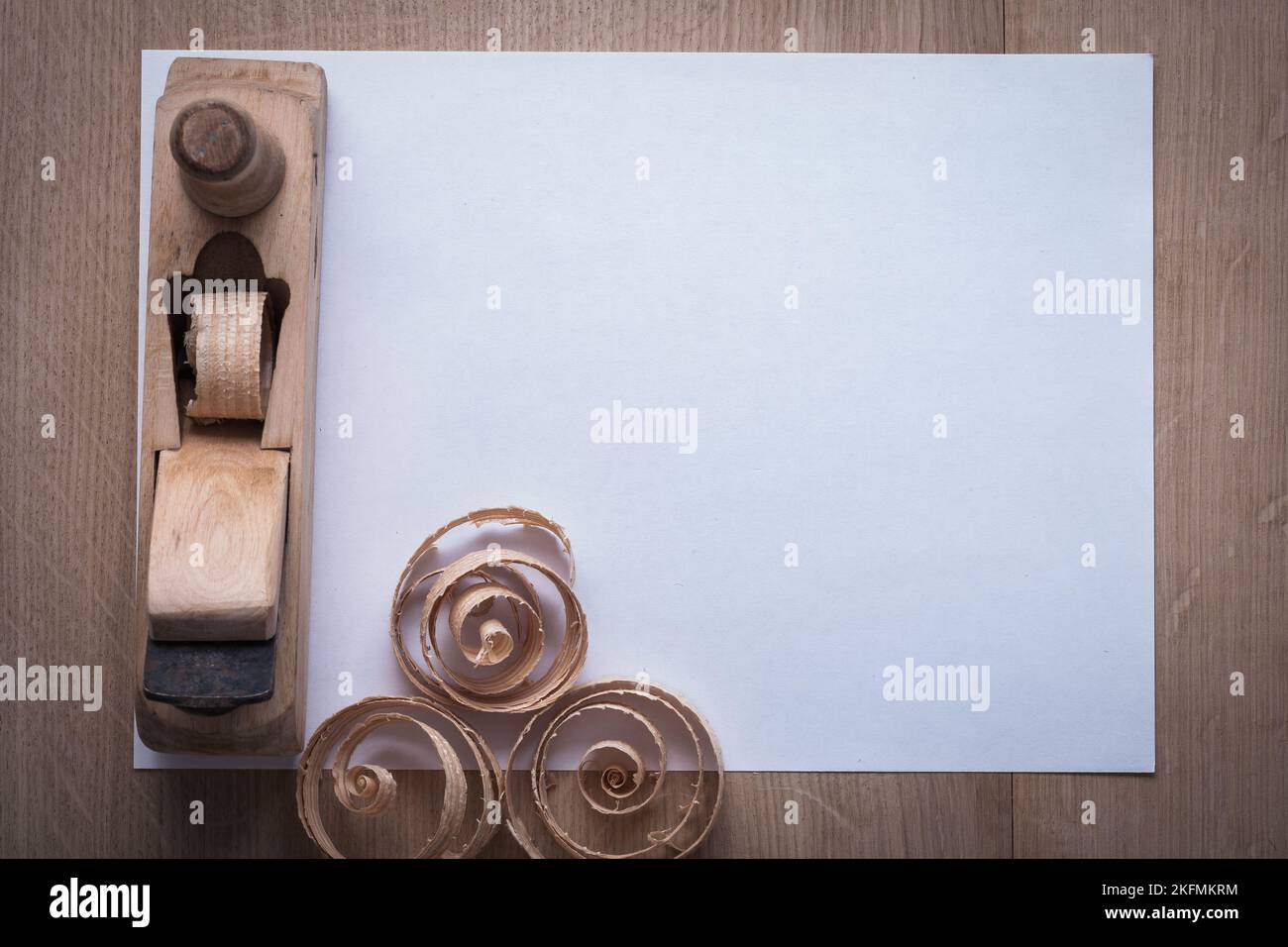Wooden planer curled planning chips and clean sheet of paper on wood ...