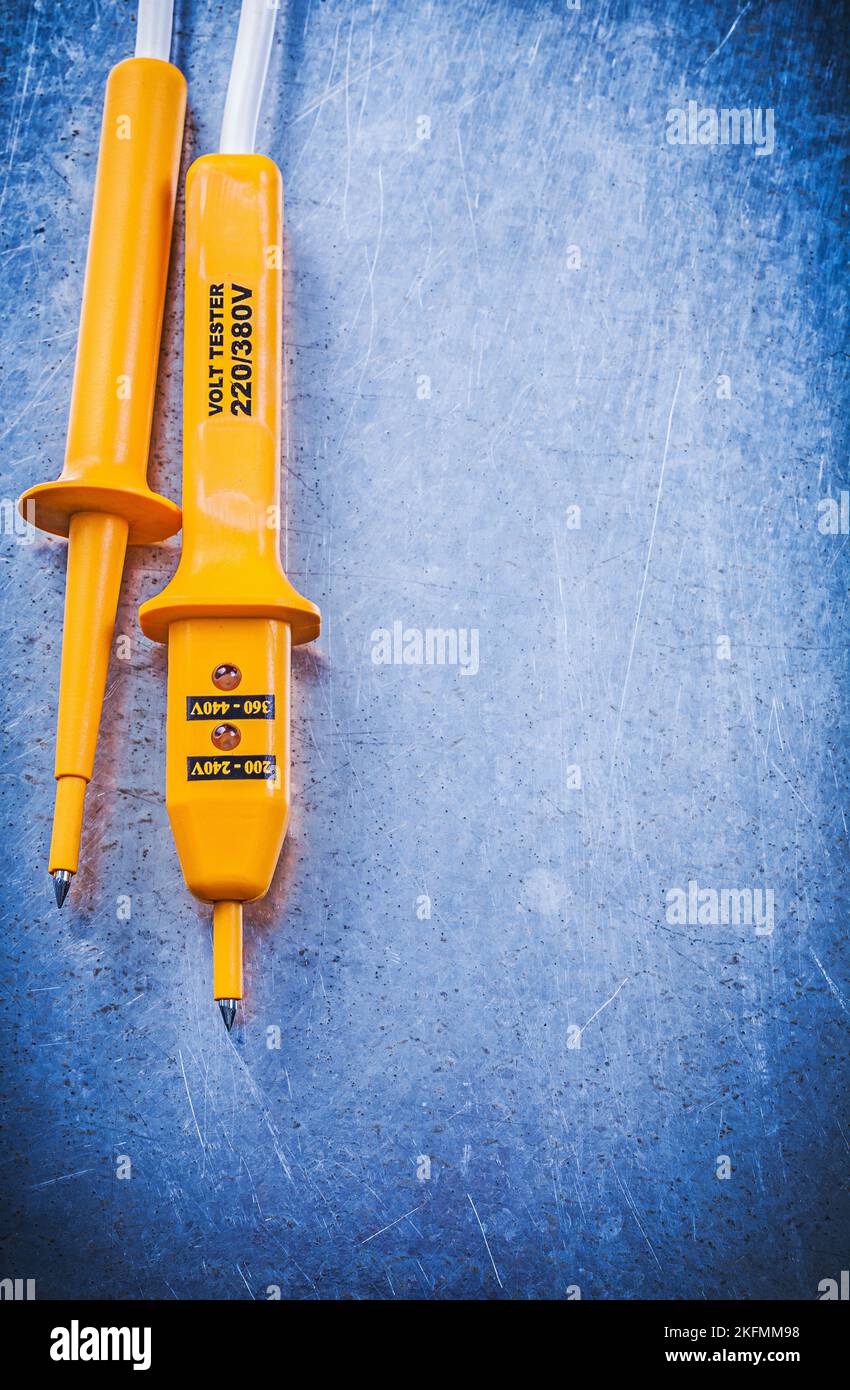Yellow electrical tester on scratched metallic background directly ...
