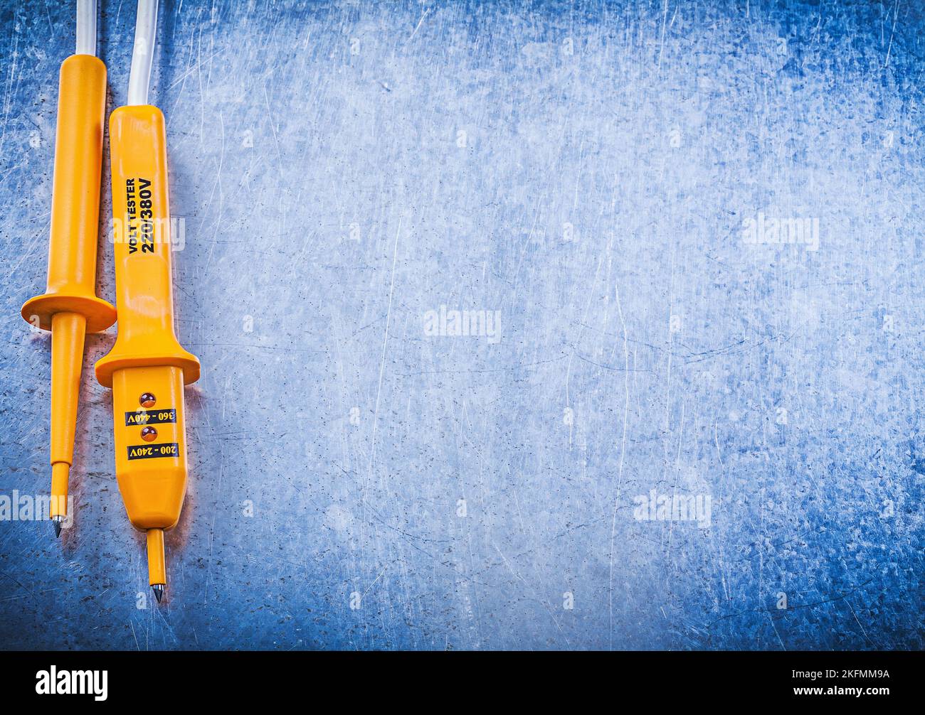 Yellow electrical tester on scratched metallic background electricity ...