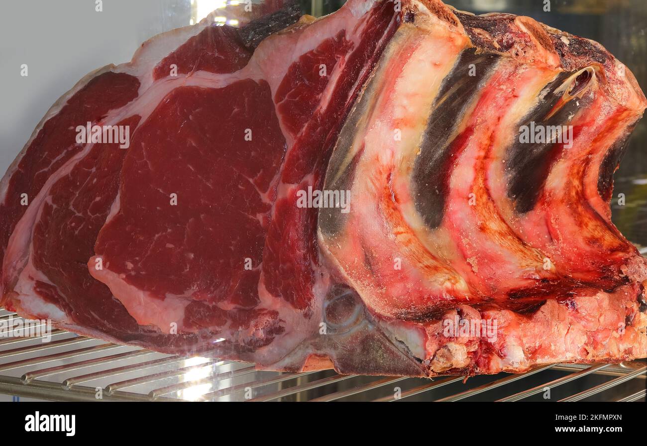 large piece of raw red meat in the industrial freezer of the butcher's ...