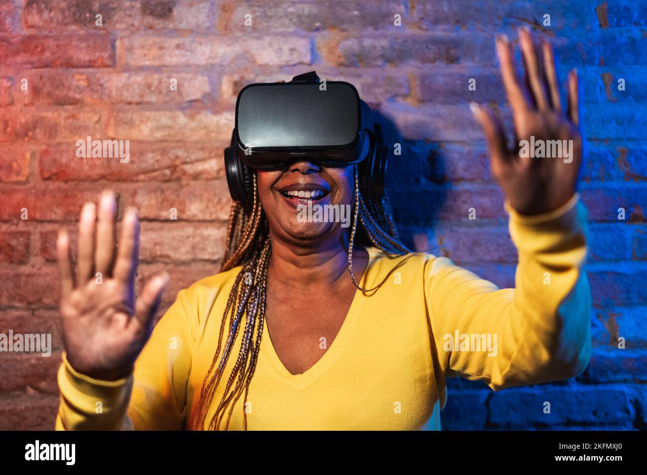 Senior African woman having fun with futuristic virtual reality goggles ...