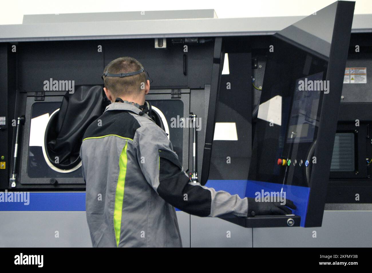 The worker controls workflow inside large industrial 3D printer ...