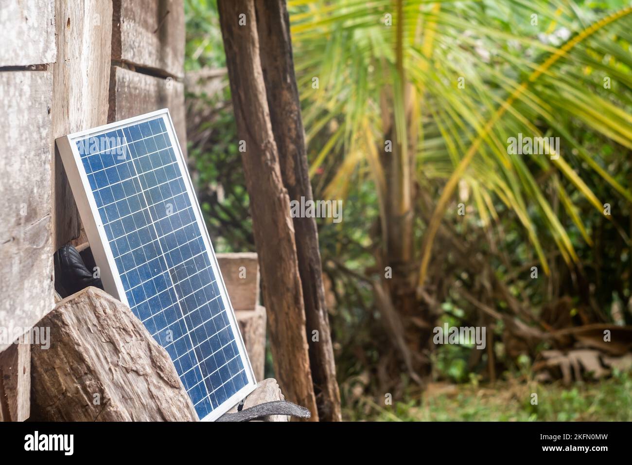 A closeup of a solar panel leaning on the side of a wooden house in a ...