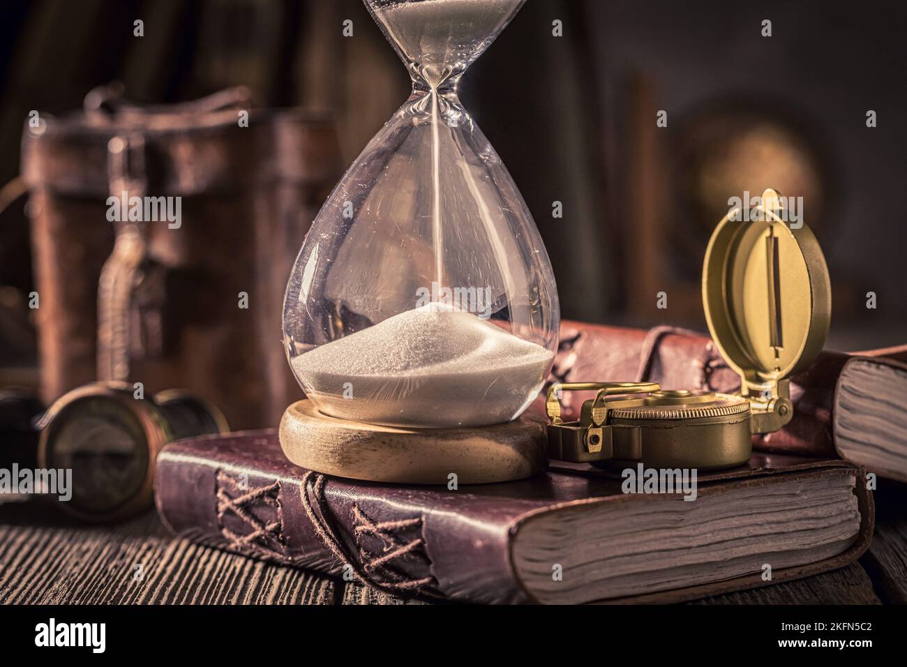 Old hourglass and journal with binocular, books and compass. Symbol of ...
