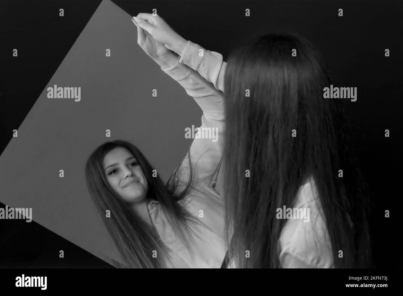 Black and white portrait of young woman looking at her reflection in ...