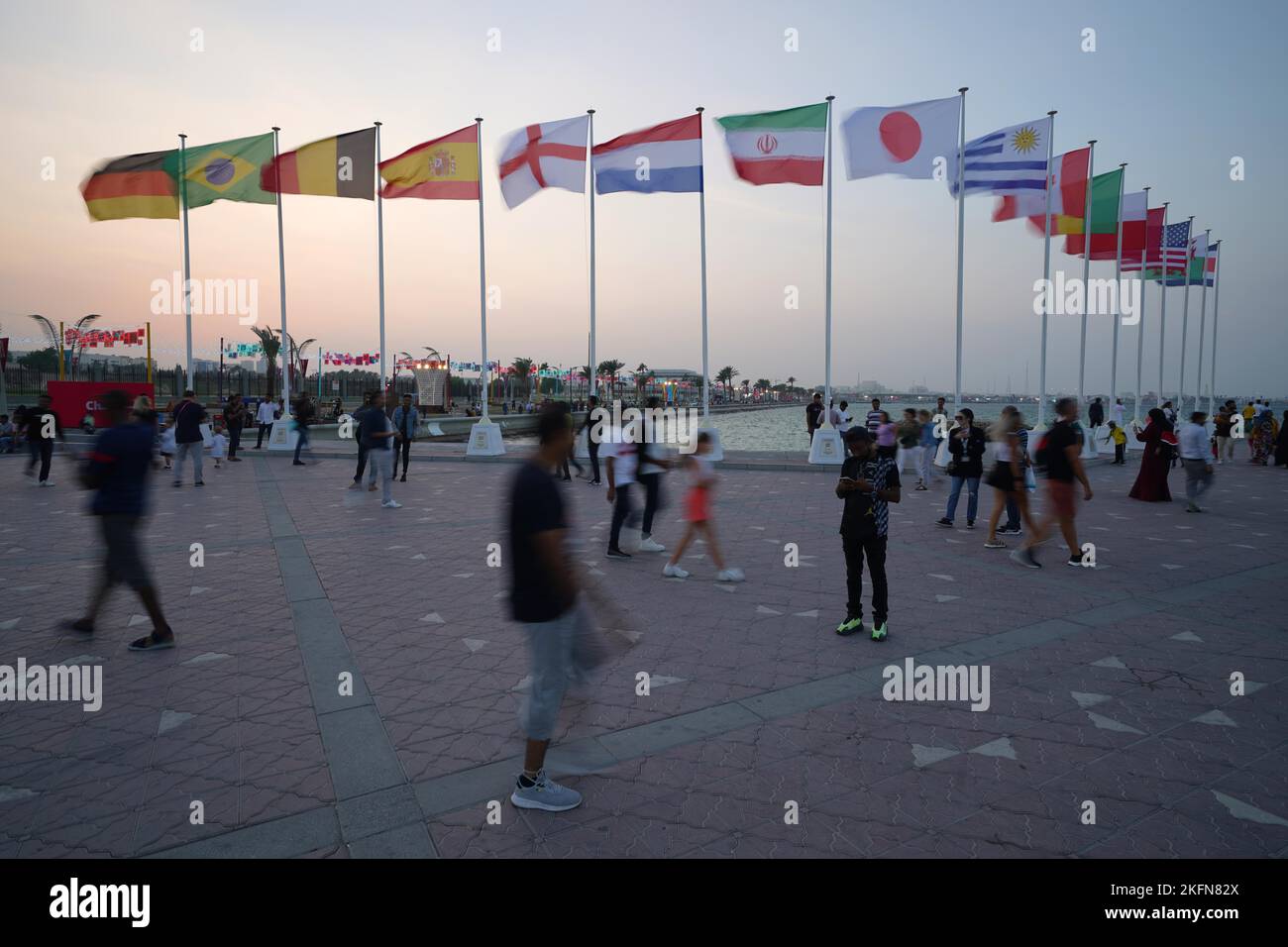 People walk past World Cup team flags on the Corniche in Doha, Qatar ...