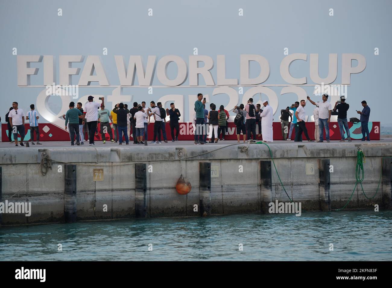 People talk pictures of a World Cup sign on the Corniche in Doha, Qatar ...