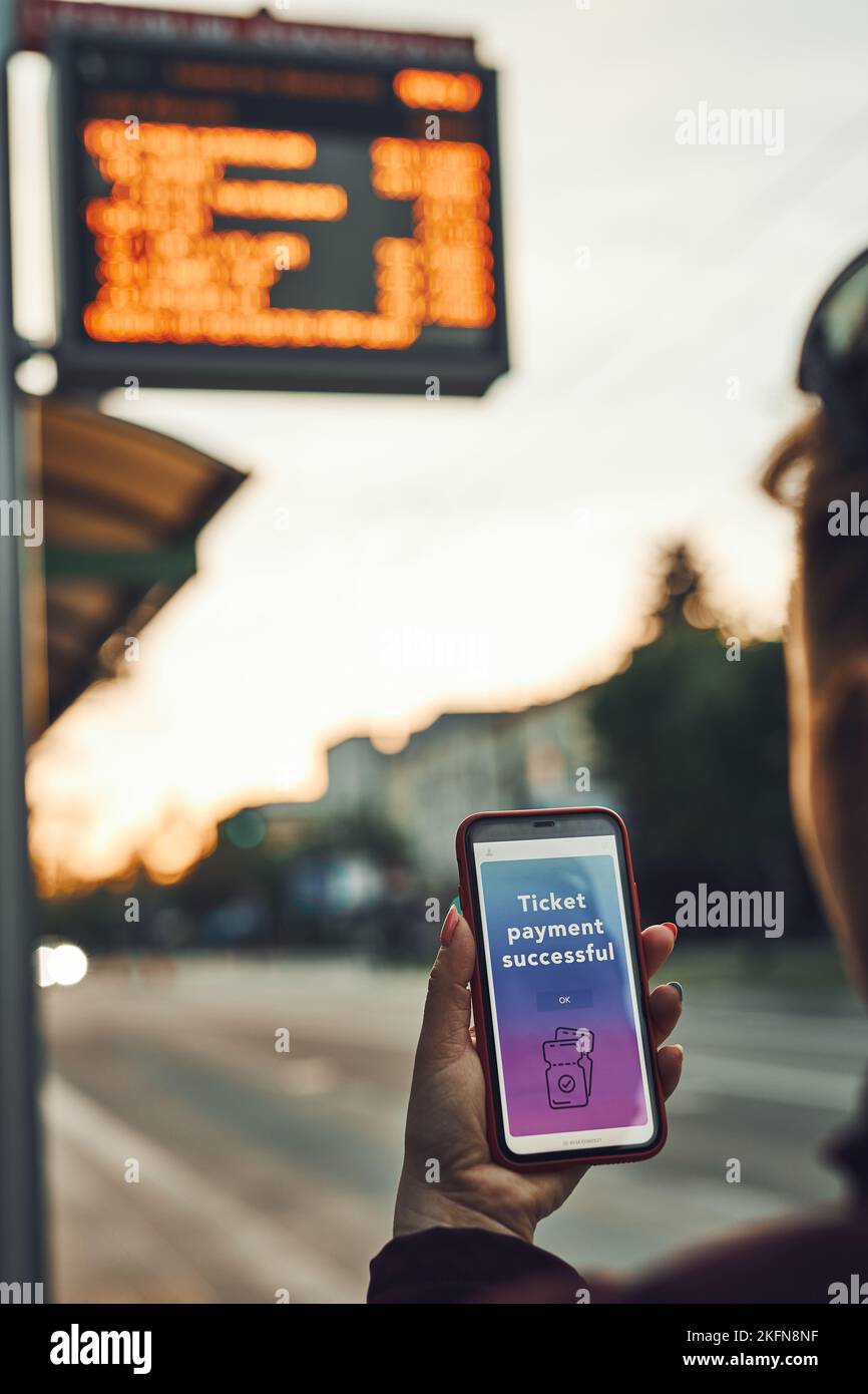 Woman buying ticket online at bus stop before ride. Person paying for ...
