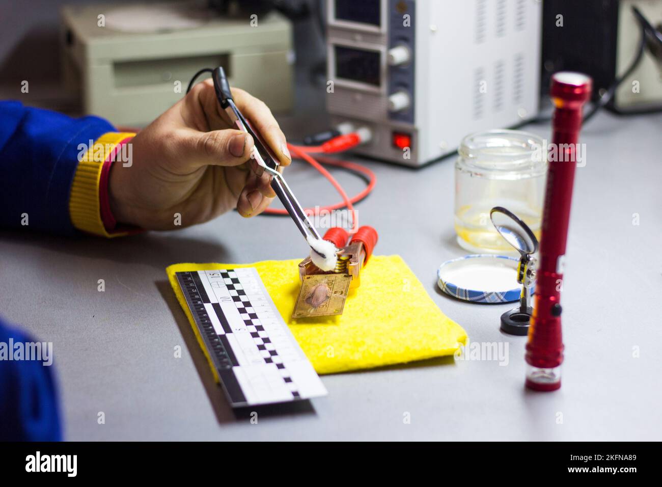 Hands of an expert hold terminals with a metal object while conducting ...