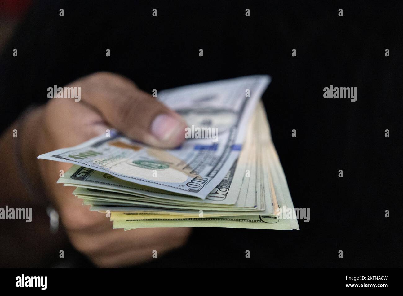 Hand holding cash in black background Stock Photo - Alamy