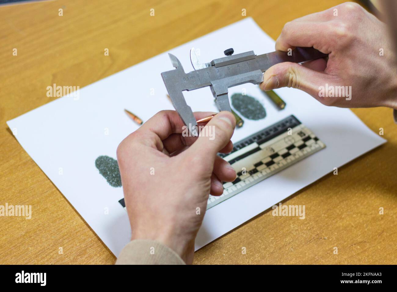 Men's hands with a caliper measure a bullet Stock Photo - Alamy