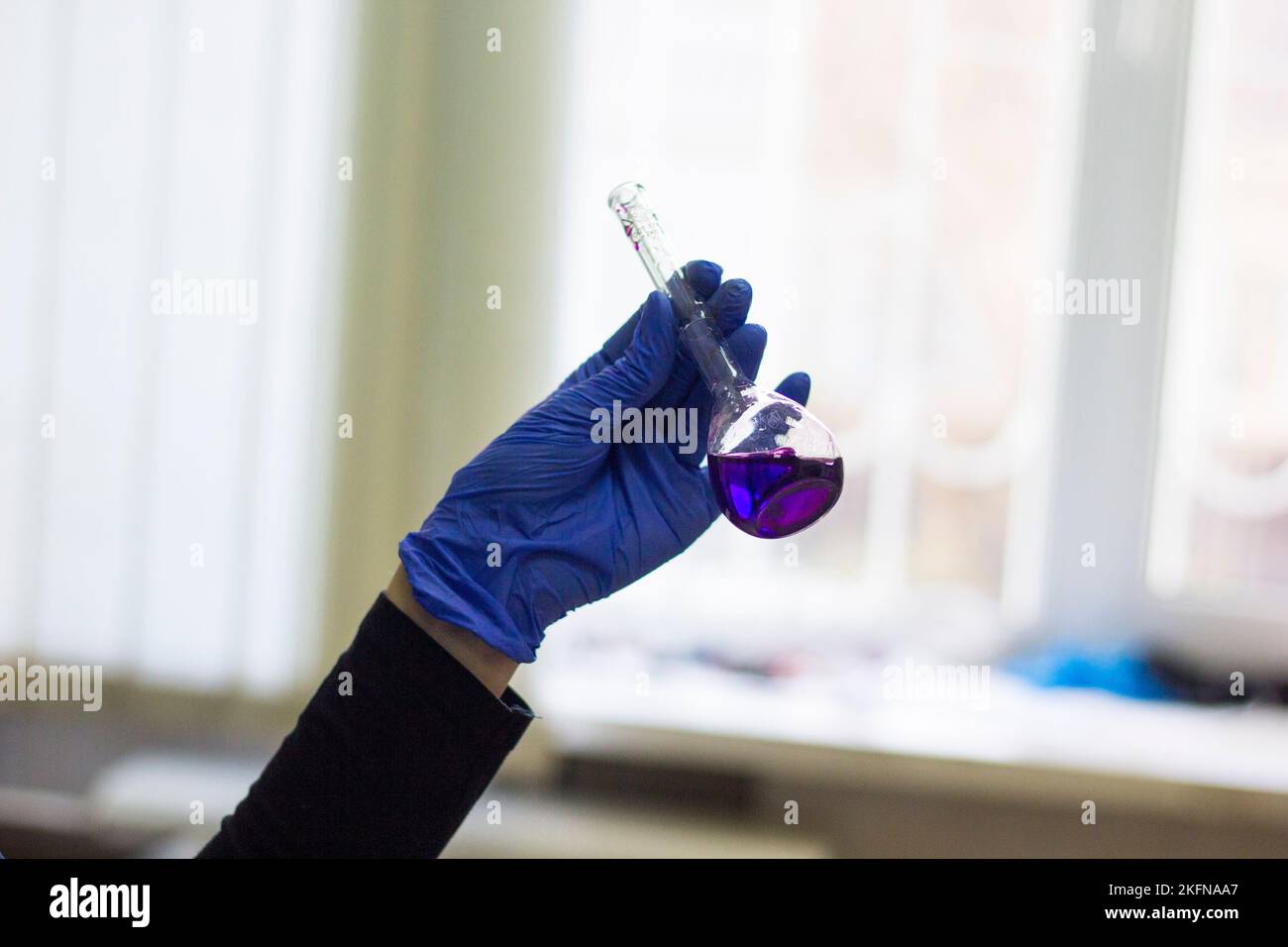 A gloved hand holds a vial with a purple solution Stock Photo - Alamy