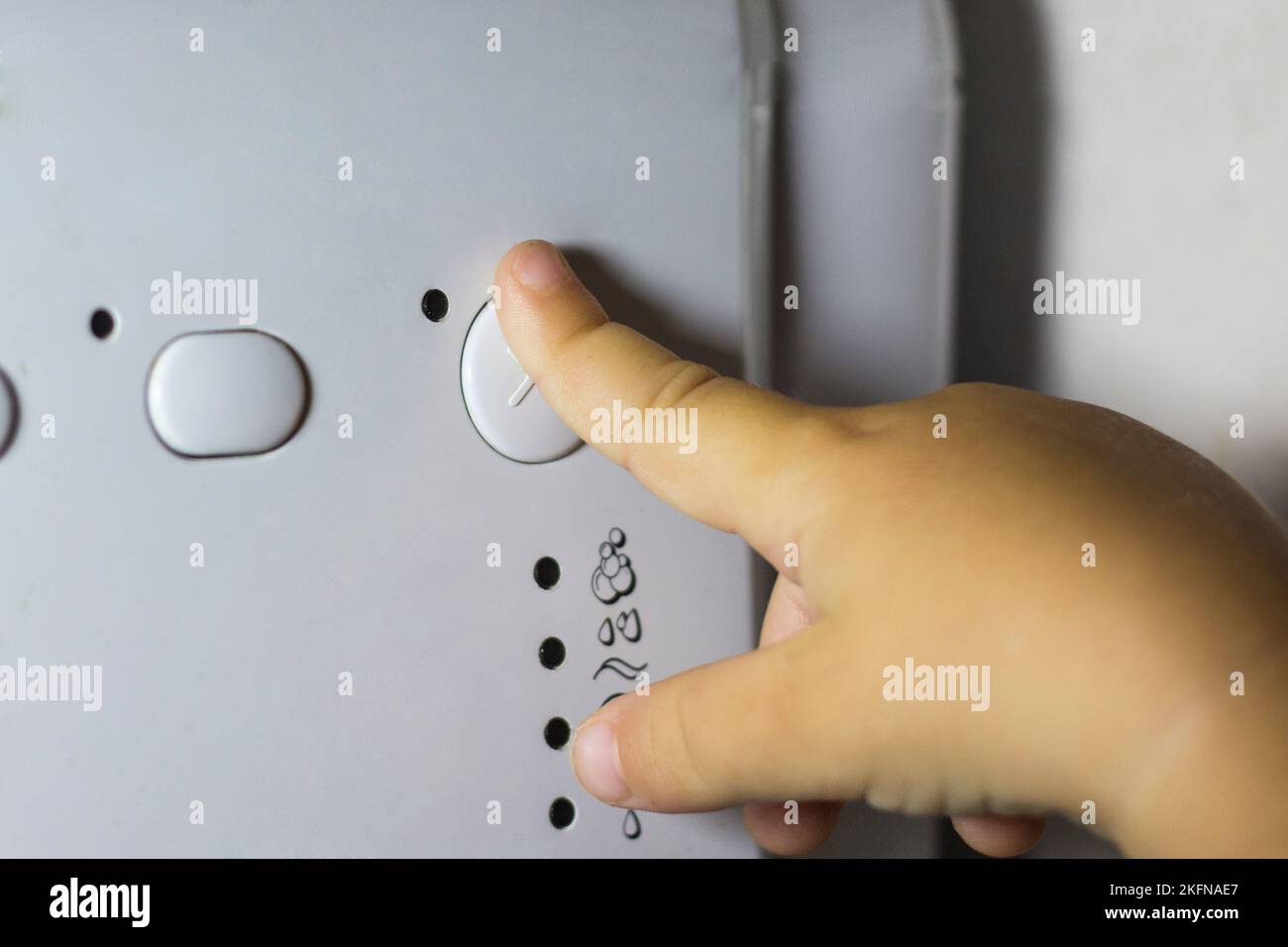 A child's hand presses a button on a washing machine Stock Photo - Alamy