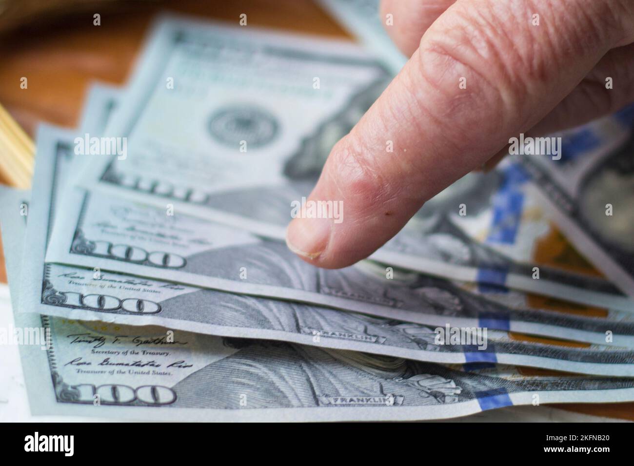 The female hand of an elderly woman points her finger at the dollar ...