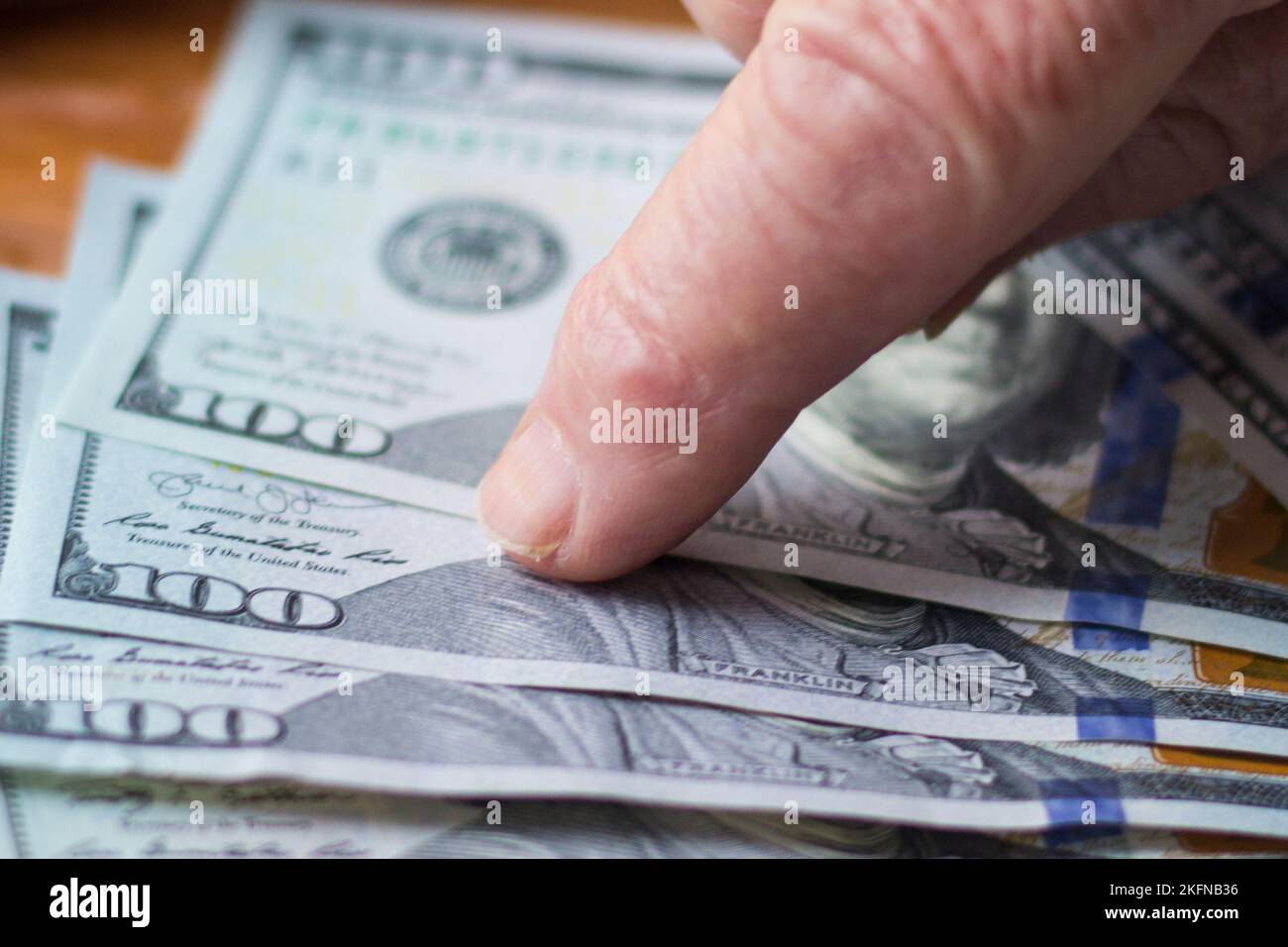 The female hand of an elderly woman points her finger at the dollar ...