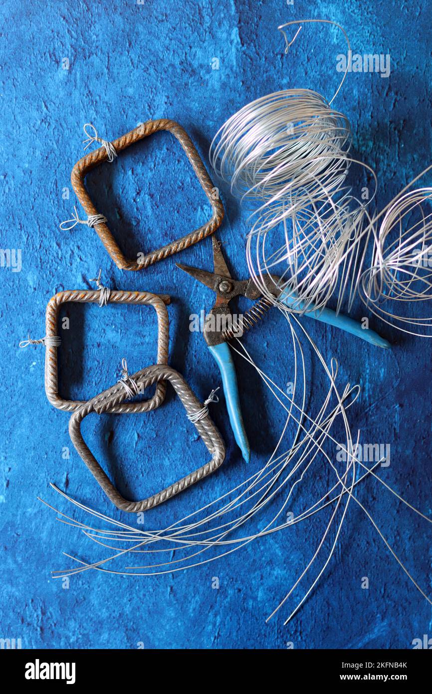 Steel wire and blue pliers close up photo. Craftsman tools on a ...