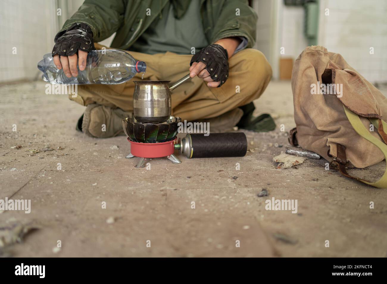Post-apocalypse. Close up hands of man sits on floor of an abandoned ...