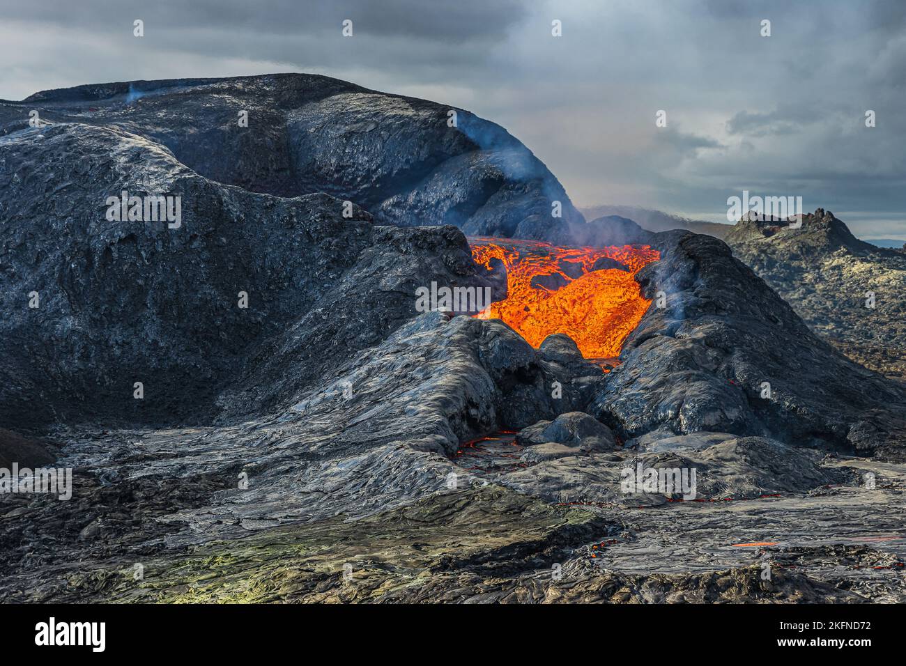 Lava flows from a volcanic crater. hot reddish liquid magma from the ...