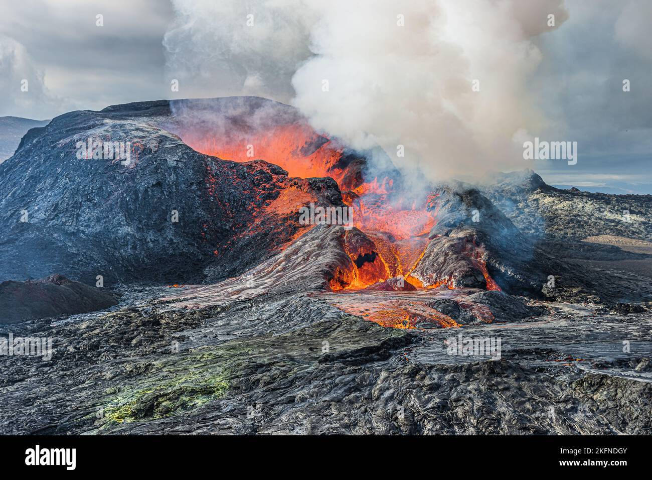 Heavy steam and smoke over a volcanic crater. glowing red lava flows ...