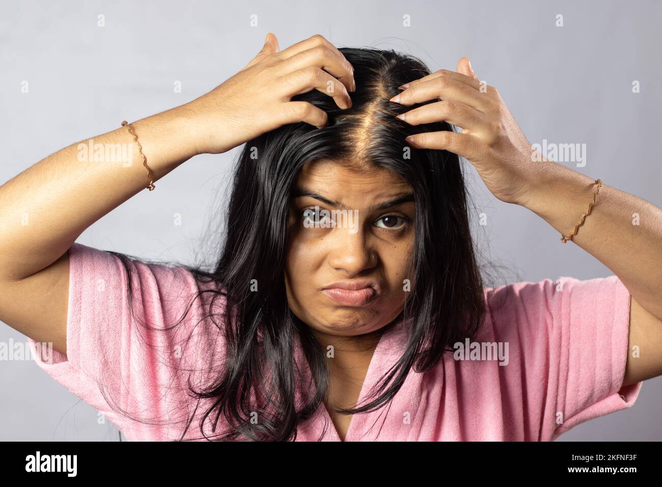 An Indian woman worried due to hair loss problem holds scalp on white ...