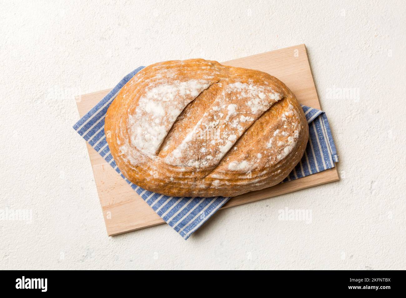 Freshly baked bread on cutting board against white wooden background ...