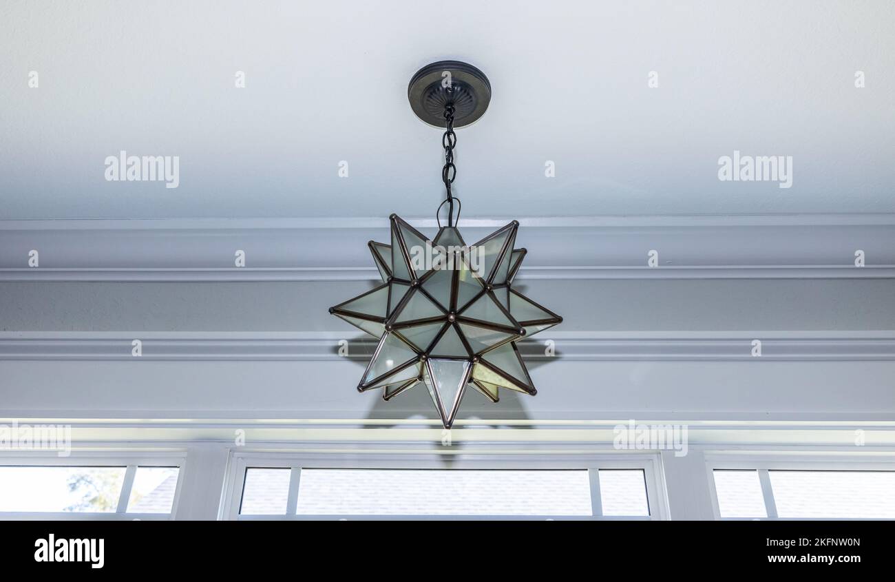 A metal and glas star shaped hanging lighting fixture near a large ...