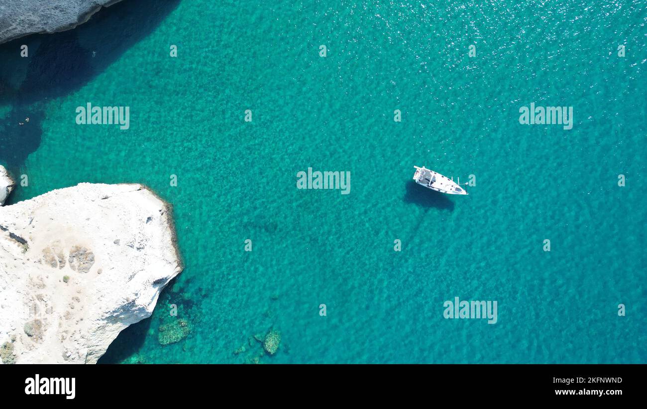 A bird's eye view of a white boat sailing on crystal-clear blue water ...