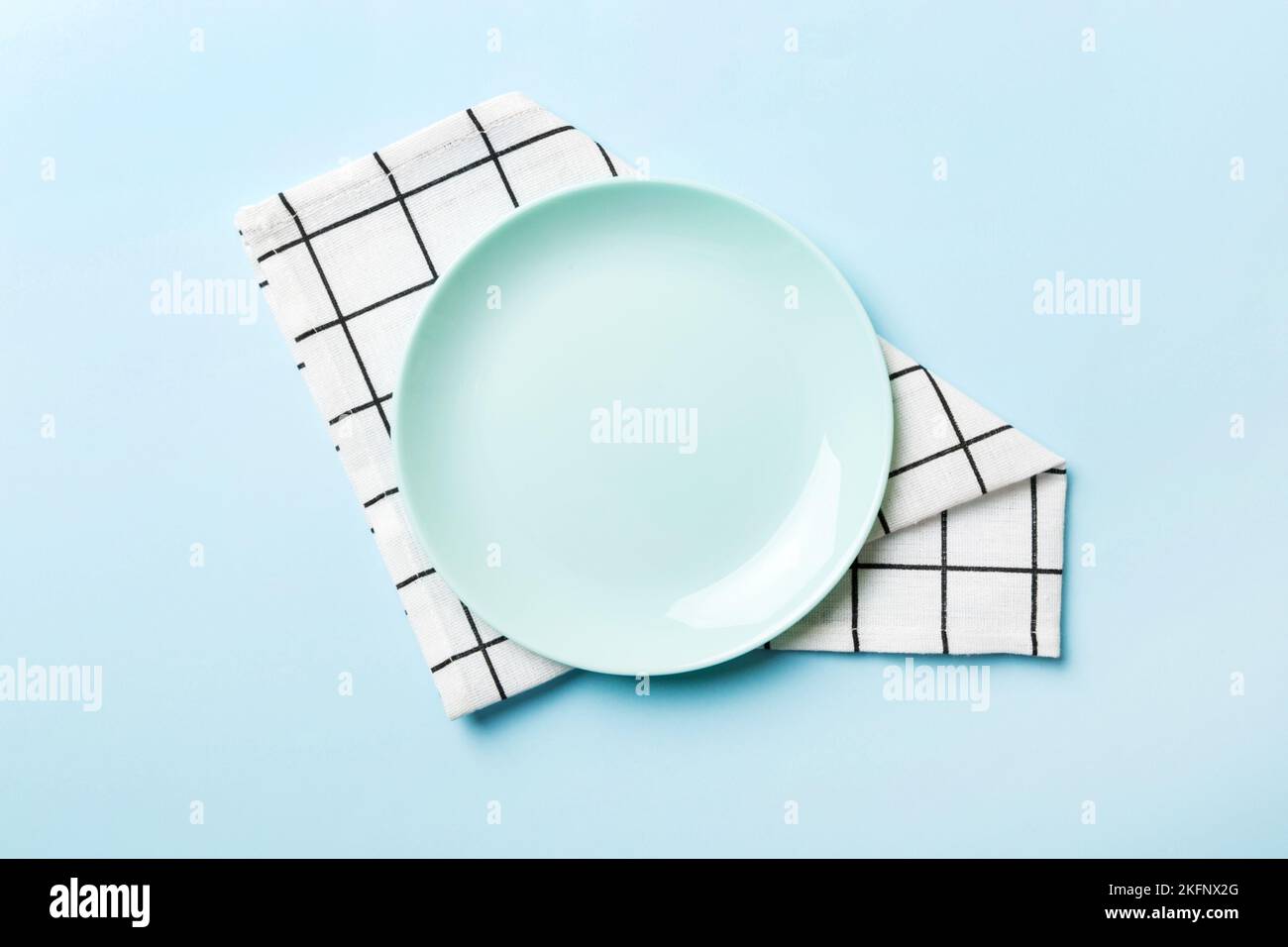 Top view on colored background empty round Blue plate on tablecloth for ...