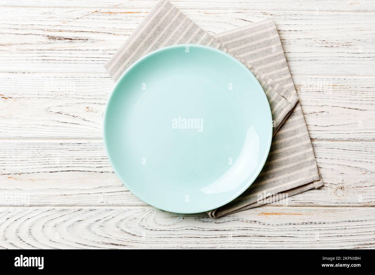 Top view on colored background empty round Blue plate on tablecloth for ...