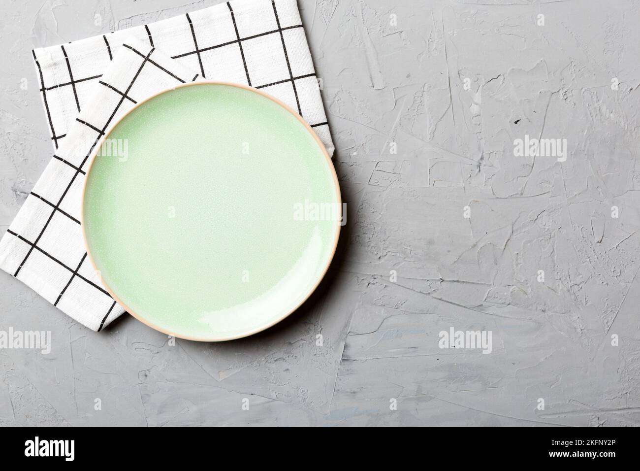 Top view on colored background empty round green plate on tablecloth ...