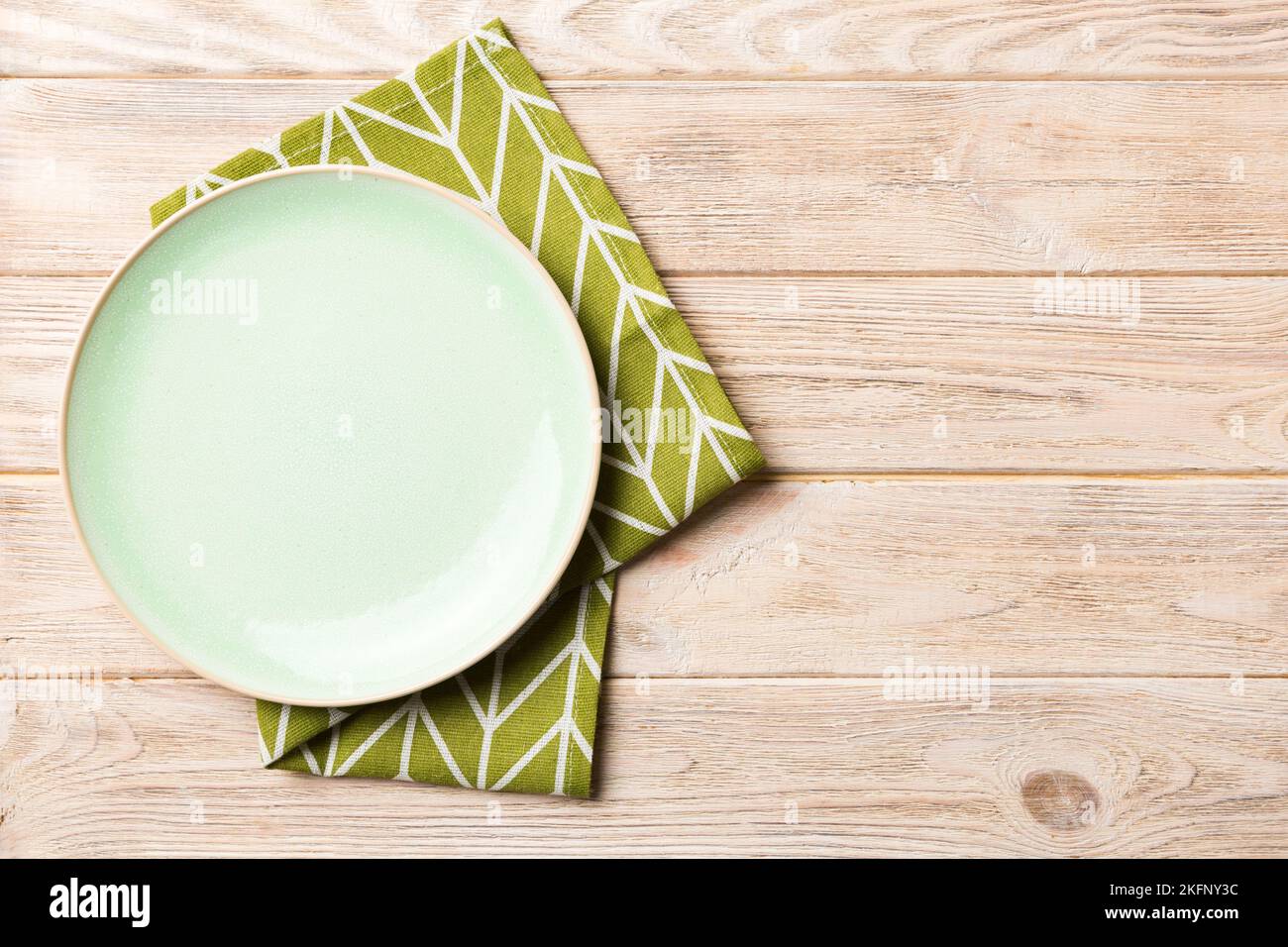 Top view on colored background empty round green plate on tablecloth ...