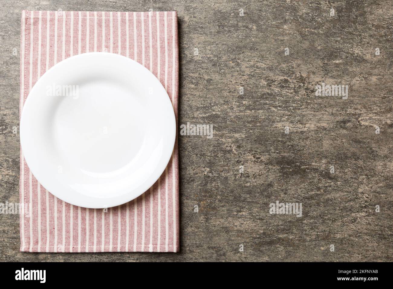 Top view on colored background empty round white plate on tablecloth ...