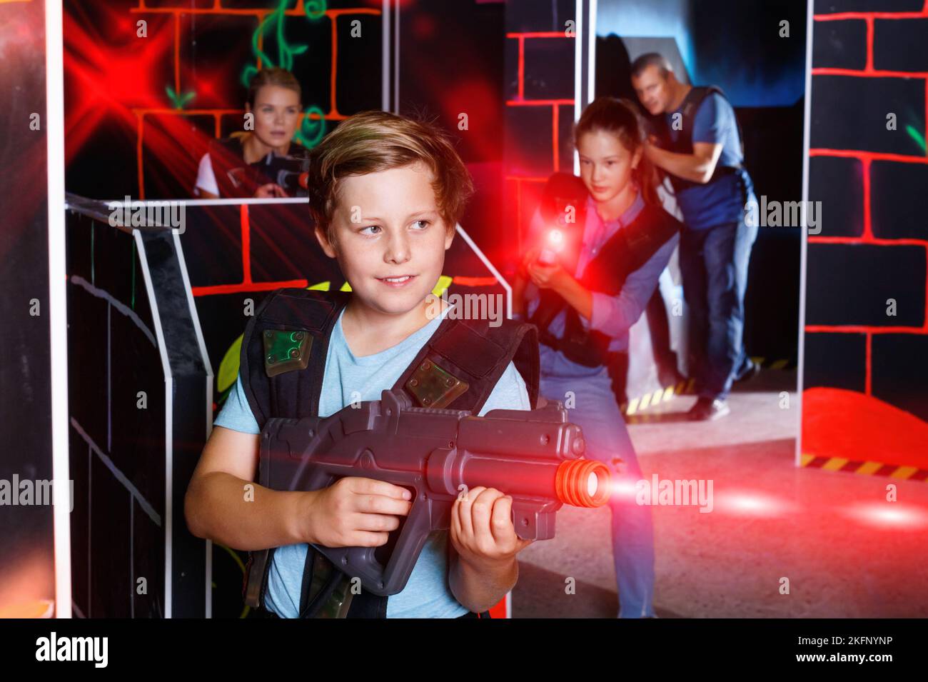 Excited boy aiming laser gun at other players during laser tag g Stock ...