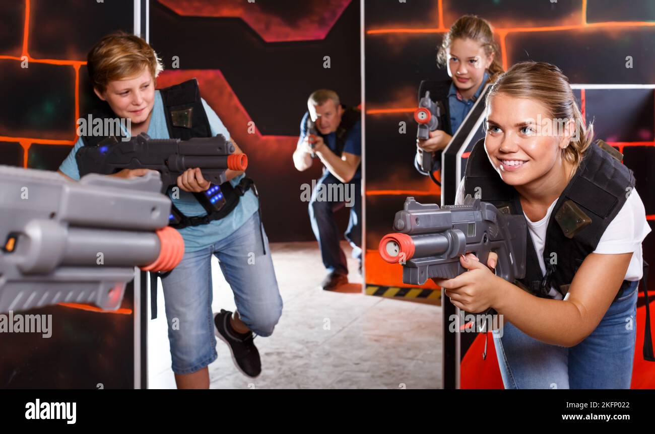 enthusiastic young parents and children with laser pistols playing ...