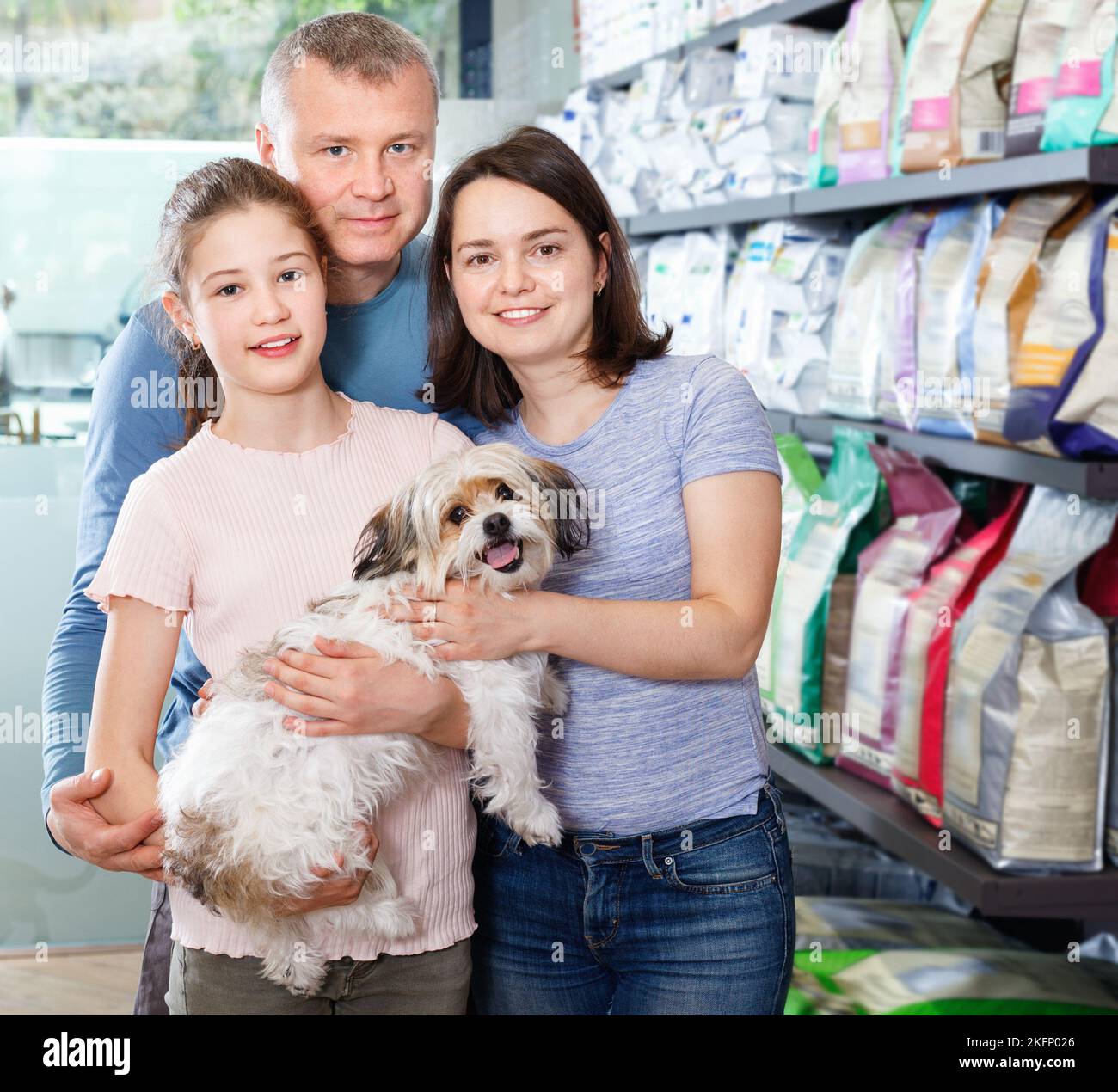 Portrait of friendly family with their puppy during visit of pet shop ...