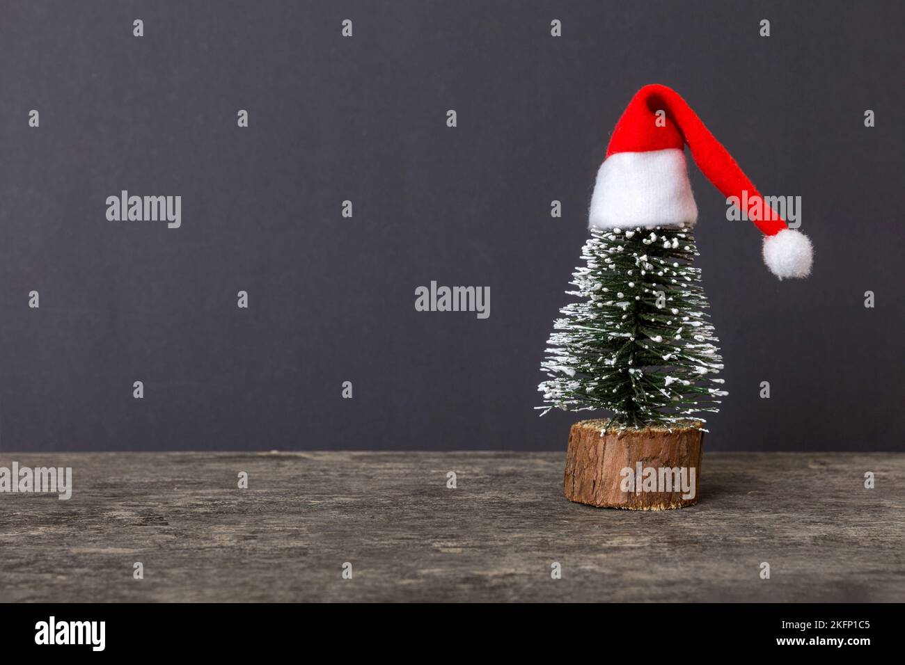 One small Christmas tree with santa hat on colored background. new year ...
