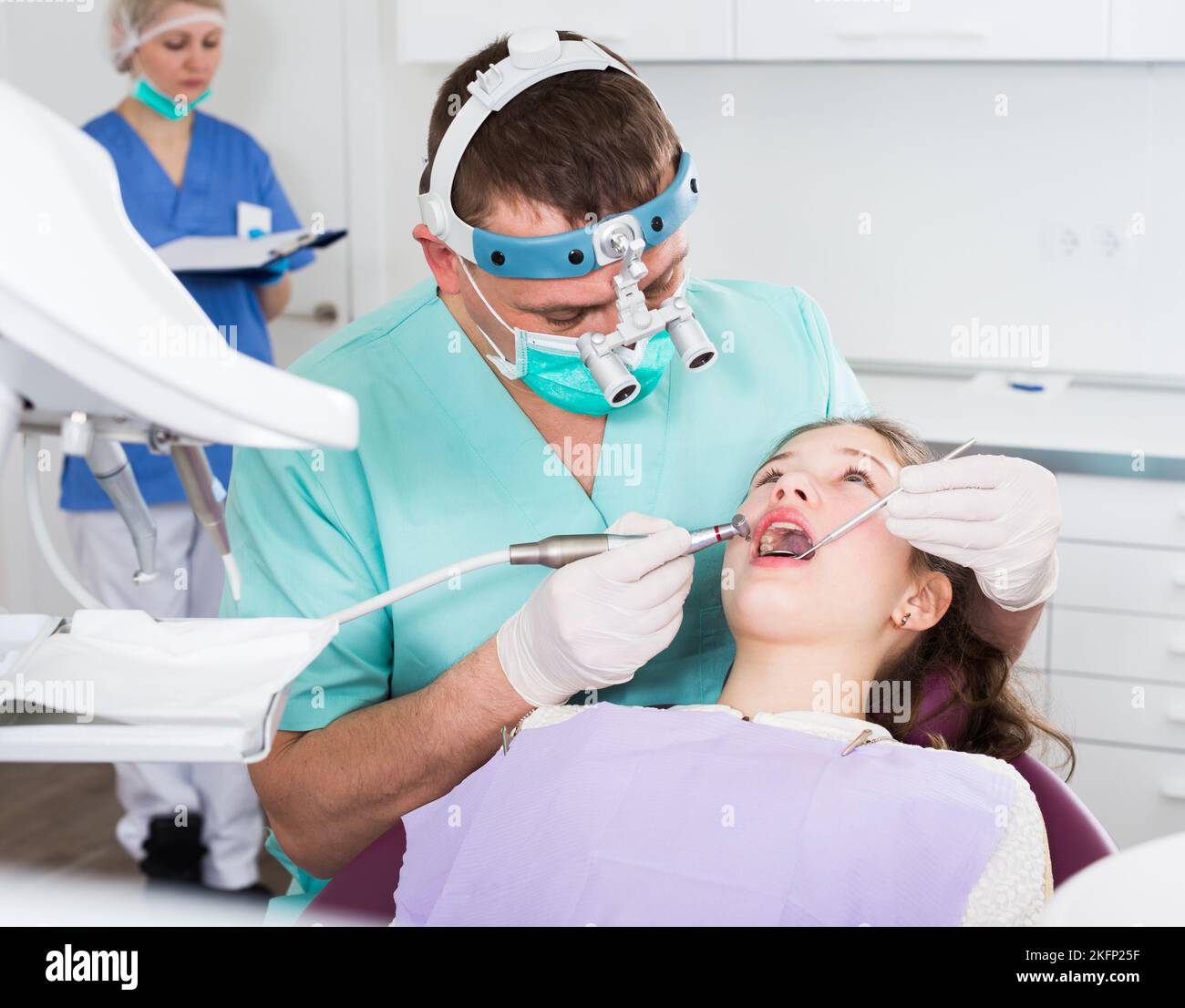 Confident male dentist treating girl Stock Photo - Alamy